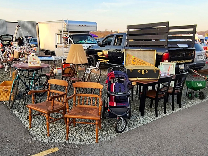 The furniture migration in its natural habitat. Wooden chairs, tables, and lamps gather at the edge of the asphalt, hoping to catch the eye of passing shoppers.
