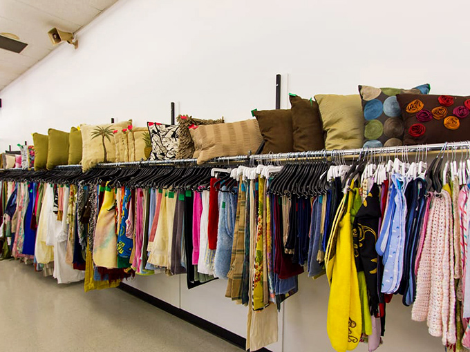 The textile treasure trove – where decorative pillows and summer dresses create an unexpected color story above the racks.