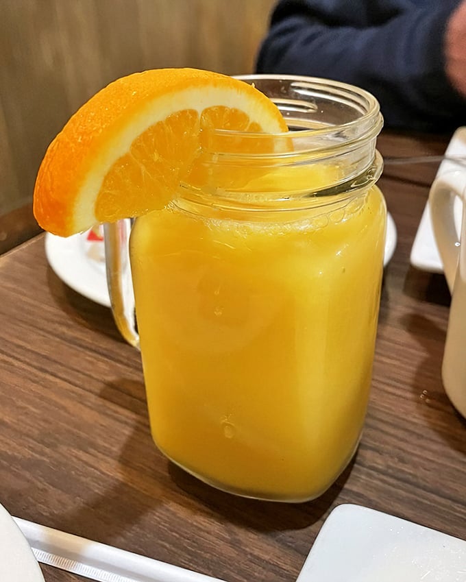 Fresh-squeezed orange juice served in a mason jar with a slice perched on the rim—liquid sunshine to wash down all that comfort food.