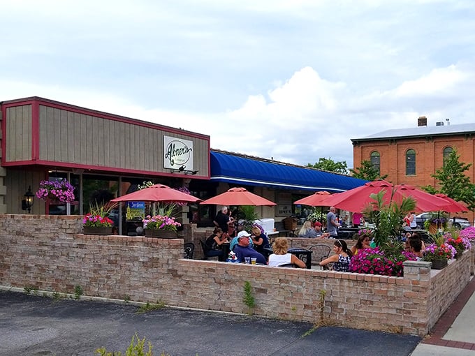 The brick-walled patio buzzes with conversation and laughter—a summer sanctuary where pink umbrellas provide shade for leisurely meals and cold drinks.