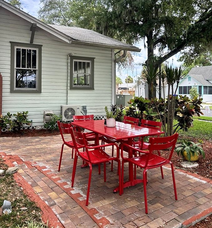 Those fire-engine red tables and chairs aren't just outdoor seating—they're beacons of hope for hungry travelers seeking respite under the gentle shade of Spanish moss.