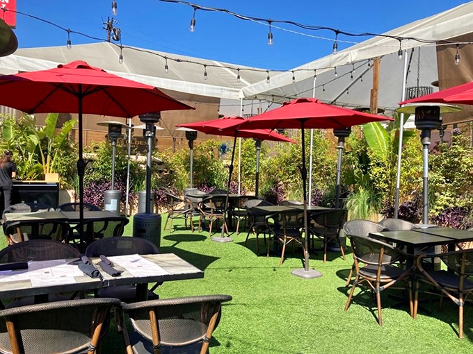 California outdoor dining at its finest – red umbrellas, lush greenery, and the promise of steak under an open sky.