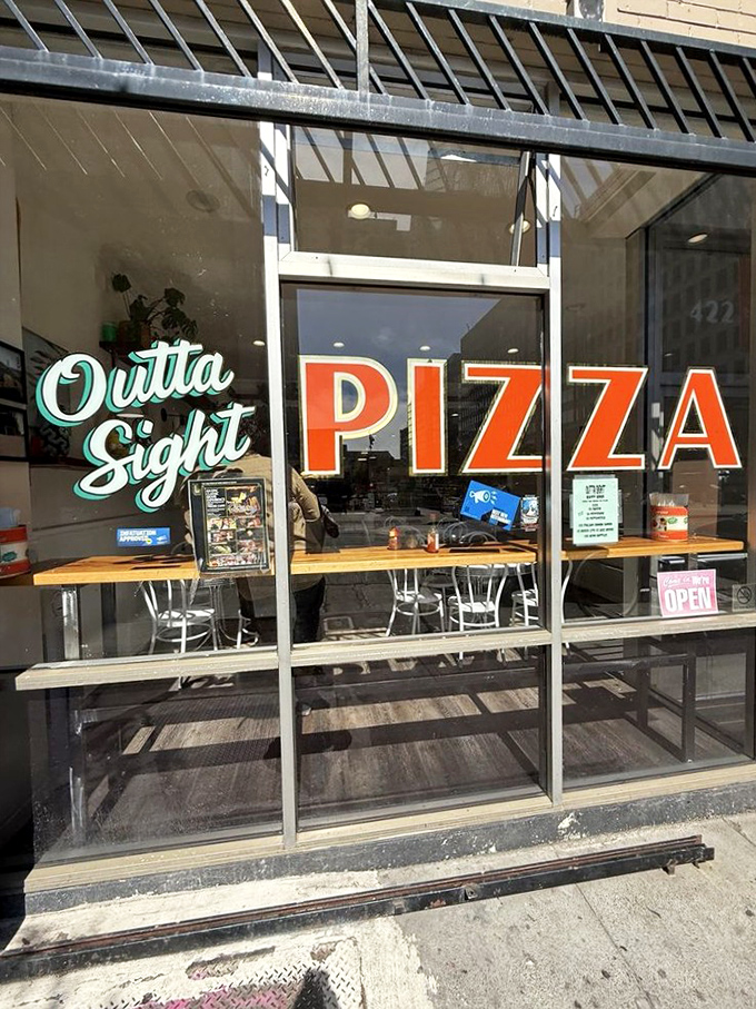 That mint script logo against bold red "PIZZA" letters—like a signature on a masterpiece. The storefront that launched a thousand cravings. 