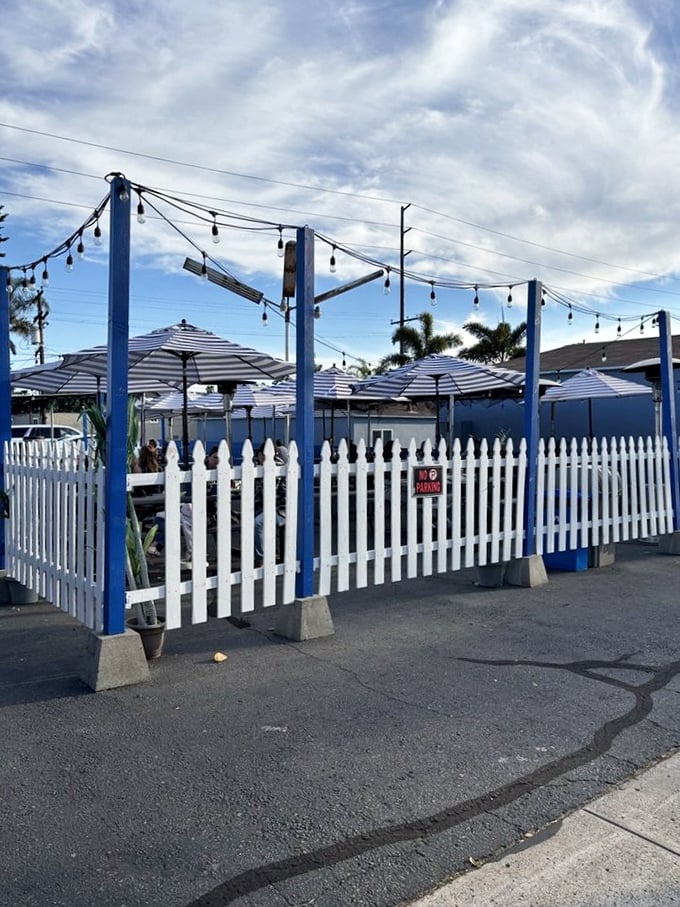The white picket fence and string lights create a coastal charm that says, "Come in, kick off your flip-flops, and stay awhile."