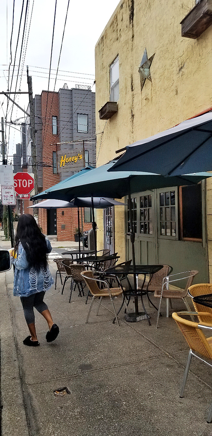 The sidewalk approach feels like discovering a secret – yellow walls, blue umbrellas, and wicker chairs patiently waiting for your breakfast stories.