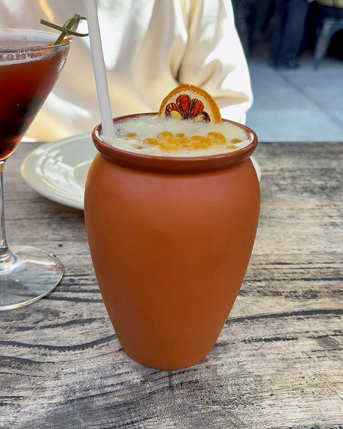 This isn't just a cocktail—it's a terracotta vessel of joy, topped with a citrus smile that says "vacation" in any language.