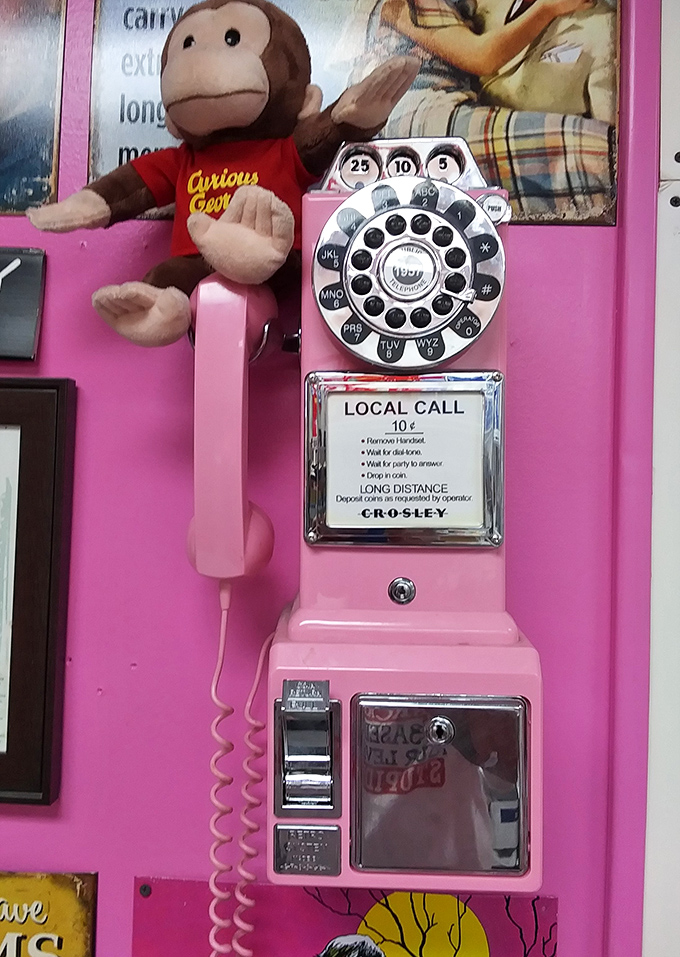 A pink payphone with Curious George standing guard – because this place understands nostalgia is the secret ingredient in comfort food.