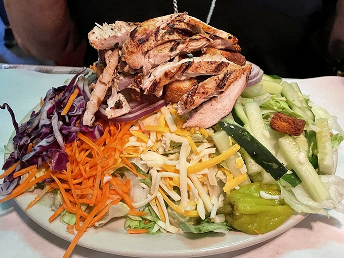 A salad so abundant it could feed a small country, topped with grilled chicken and enough fresh vegetables to temporarily convince yourself you're eating healthy.