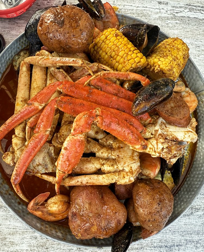 A seafood boil that's basically a treasure chest for hungry pirates—crab legs reaching skyward like they're still trying to escape their delicious fate.