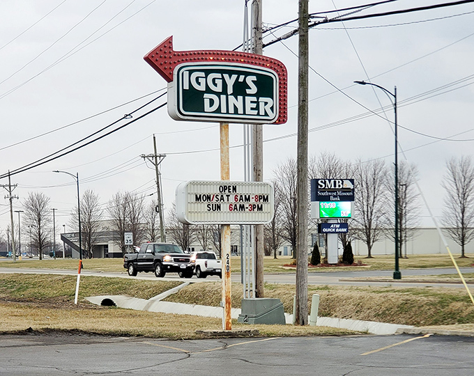 The vintage roadside sign stands tall, a neon promise of good things to come – like a lighthouse guiding hungry sailors to breakfast harbor.