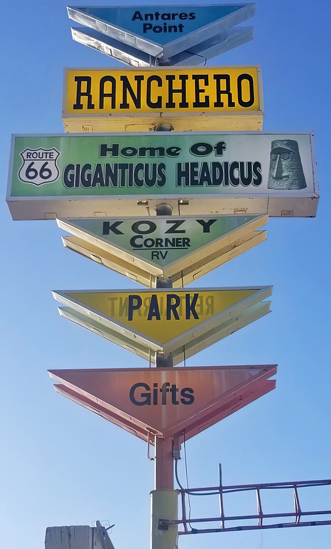 The multi-layered sign tower serves as a roadside resume—"Home of Giganticus Headicus" being the most impressive qualification on its colorful CV.