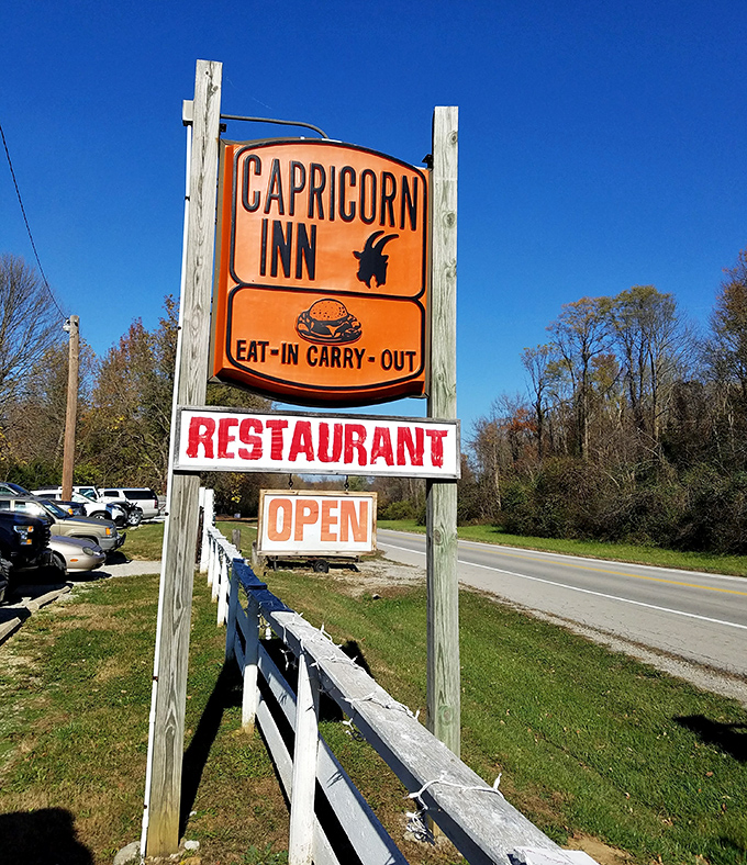 The roadside sign stands like a beacon of hope for hungry travelers—orange and confident, making promises about burgers that it fully intends to keep.