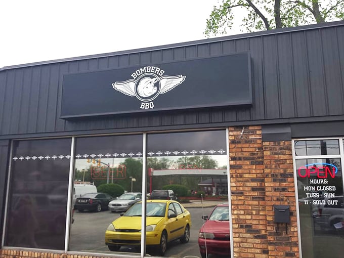 The winged logo of Bombers BBQ stands as a beacon of hope for meat lovers. Note the hours—they close when they sell out!
