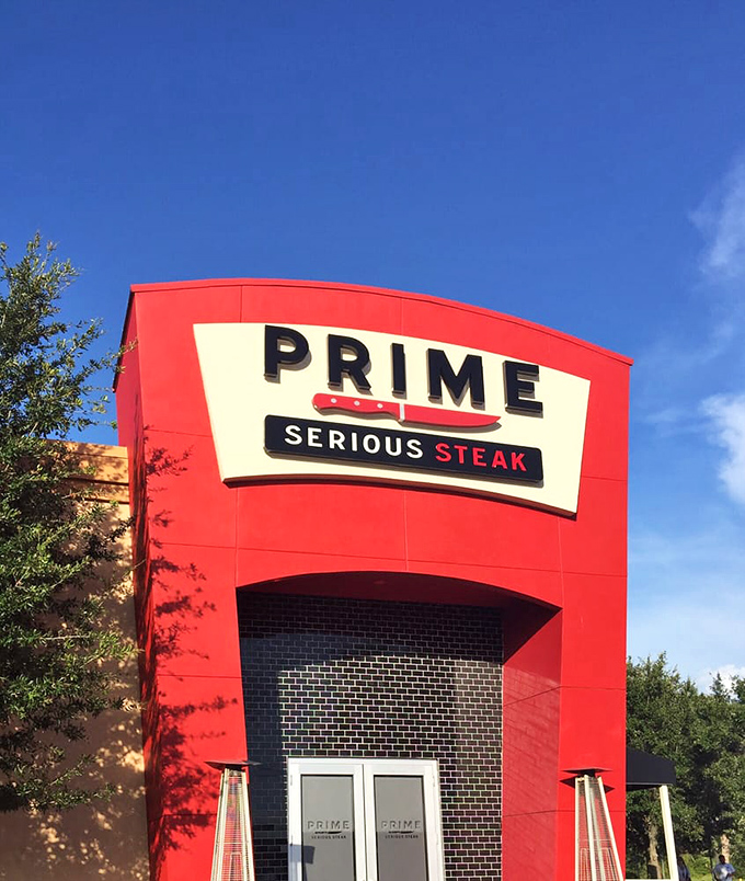 PRIME's daytime facade stands bold against Florida's blue sky. The red exterior promises passion inside – for meat, for dining, for excellence.