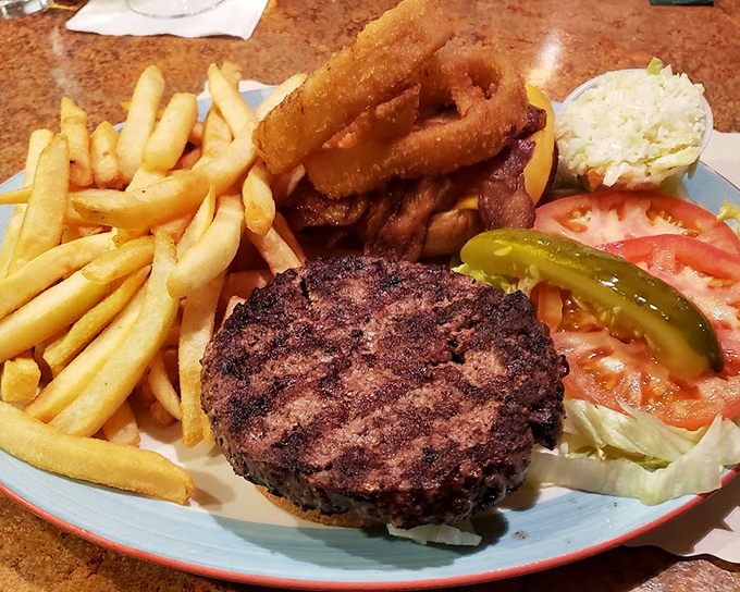 A burger that demands to be photographed before eaten, complete with the holy trinity of diner sides—fries, rings, and pickle spears.