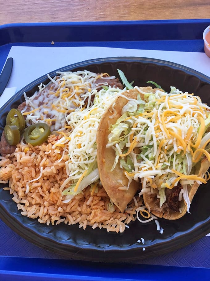 Tacos served with the trilogy of Mexican perfection: rice, beans, and jalapeños—a plate that speaks the universal language of deliciousness.