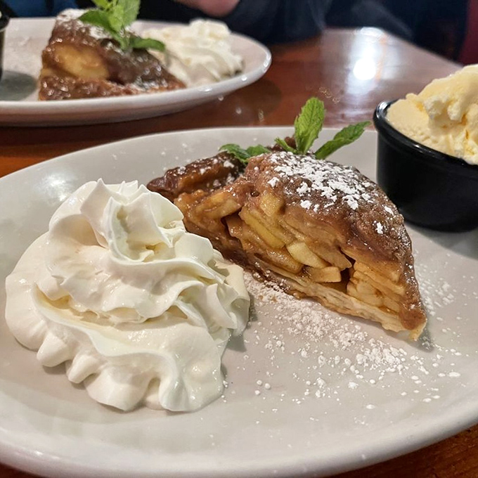 This isn't just apple pie—it's a warm, cinnamon-scented hug on a plate, complete with a cloud of whipped cream and a scoop of nostalgia.