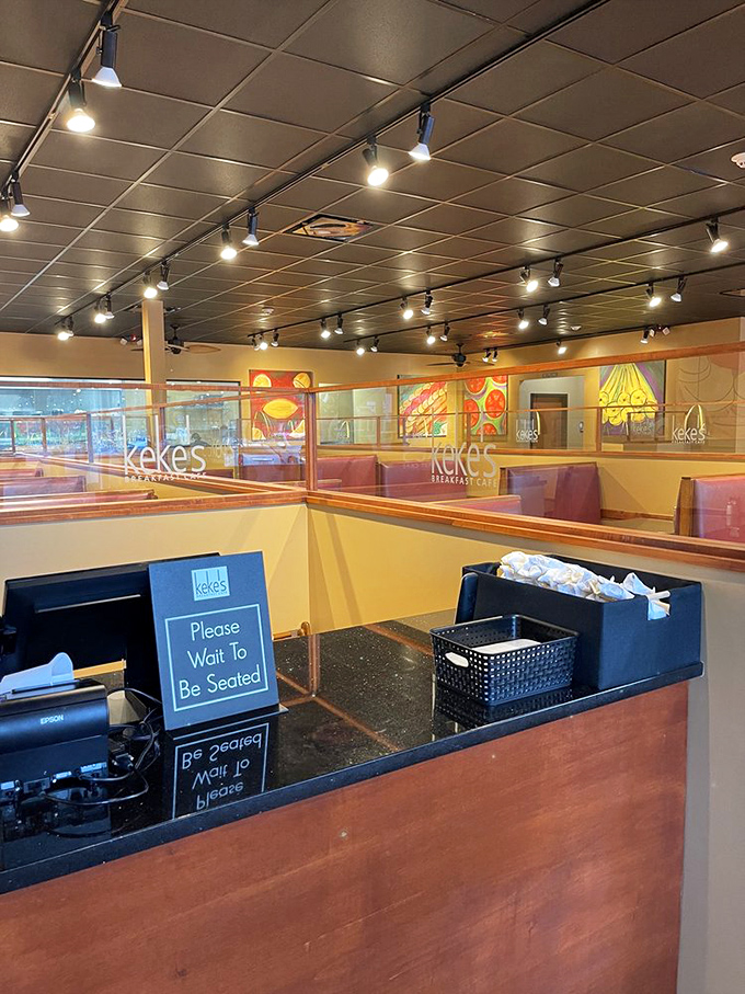 The host stand—first checkpoint on your journey to breakfast nirvana. The "Please Wait to Be Seated" sign: civilization's thin line against morning chaos.