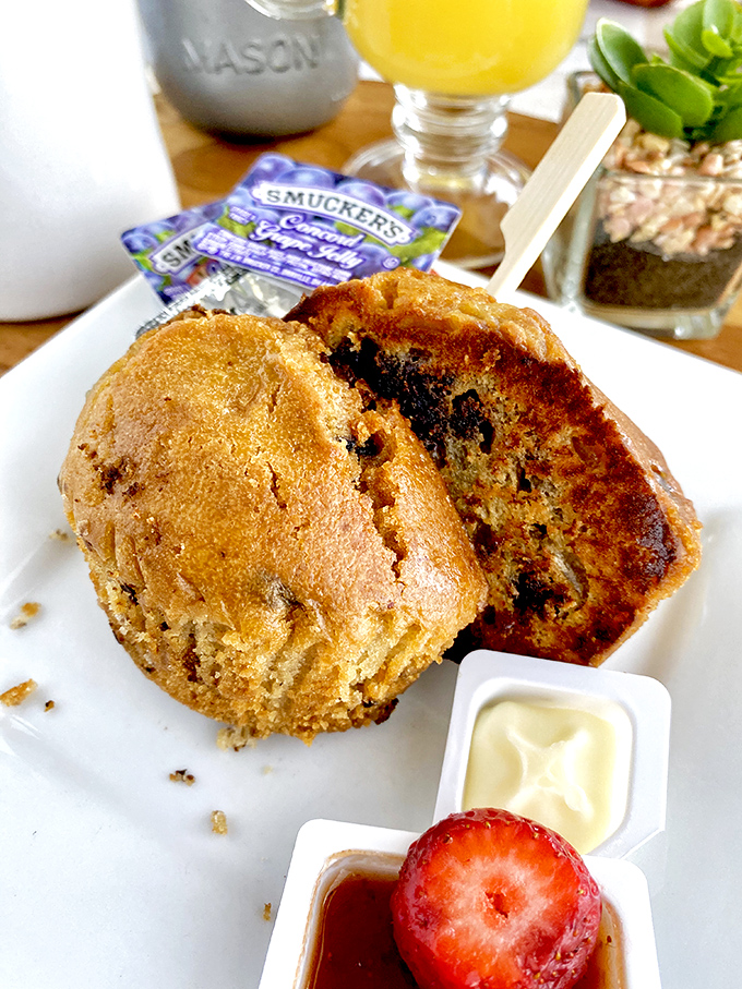 This muffin isn't just baked, it's been loved – moist, packed with what looks like chocolate chips, and served with a side of "you deserve this."