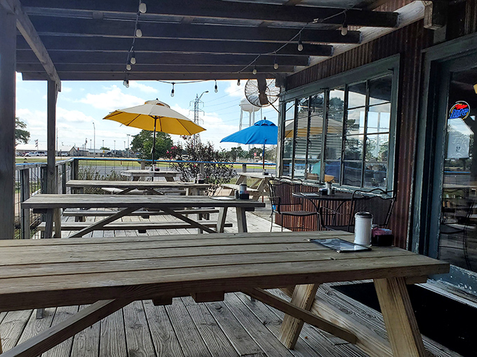 Picnic tables under Texas sky with colorful umbrellas standing guard—outdoor dining that reminds you why eating should always be this uncomplicated.