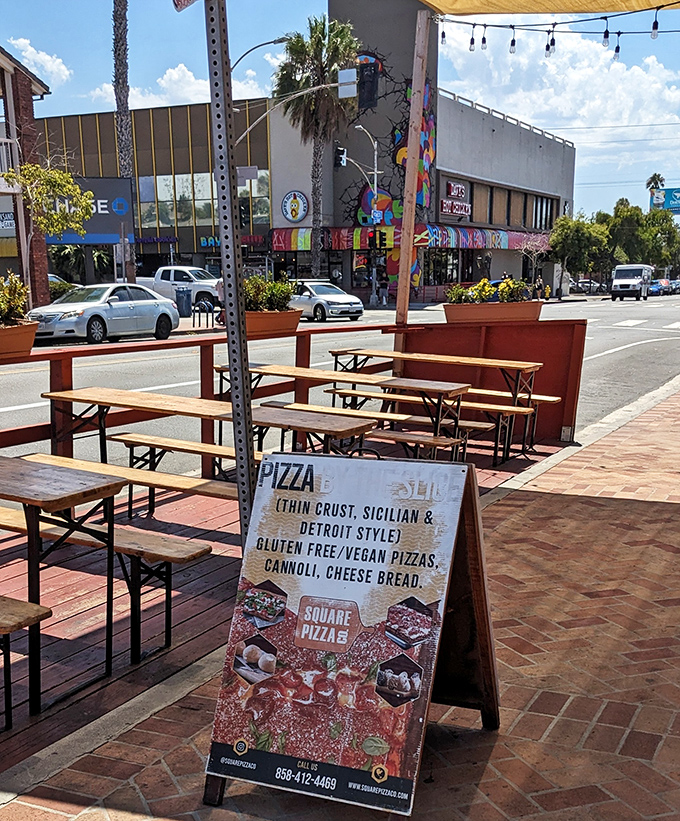 The outdoor seating area beckons like an oasis in urban San Diego. That sandwich board isn't just a sign—it's a promise of rectangular happiness.