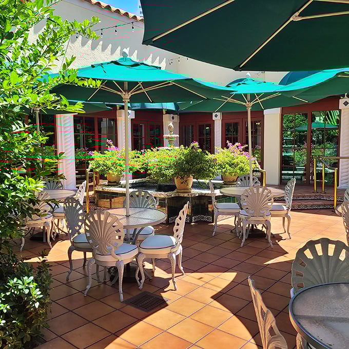 The outdoor patio offers a sun-dappled sanctuary where shell-shaped chairs and turquoise umbrellas create a perfect Florida afternoon tableau.