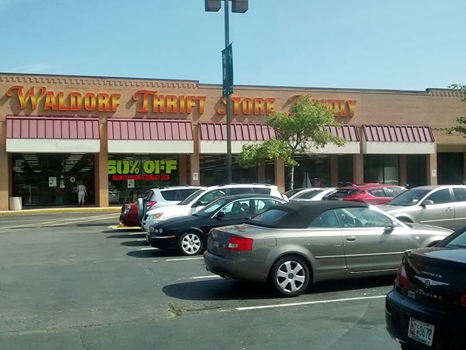 The parking lot on a sunny day, cars filling spaces as treasure hunters arrive. The "50% OFF" banner is the siren call no bargain-seeker can resist.