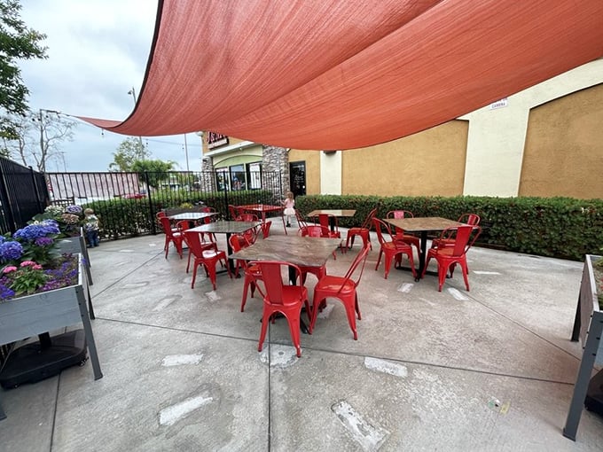 The patio where California sunshine meets casual dining. Those red chairs aren't just seating—they're invitations to linger over coffee and conversation.