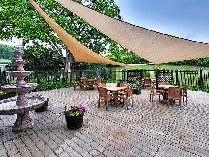 Outdoor dining under sail-like canopies with a bubbling fountain nearby. Al fresco perfection that makes summer meals feel like a countryside retreat.