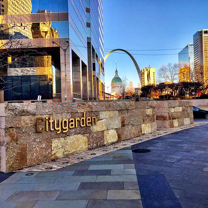 The Gateway Arch peeks into view beyond Citygarden's entrance. This perfect framing reminds visitors they're experiencing art in the heart of St. Louis.