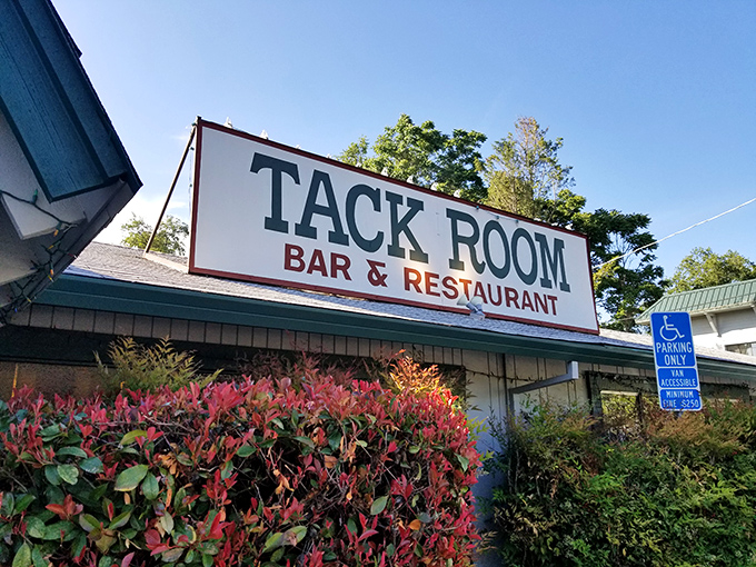 The Tack Room sign framed by vibrant foliage—like nature itself is giving this steakhouse a standing ovation.