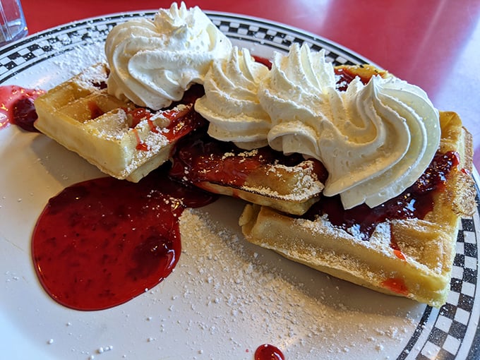 Waffles that strike the perfect balance – crisp exterior, fluffy interior, and topped with whipped cream that melts into the warm strawberry sauce.