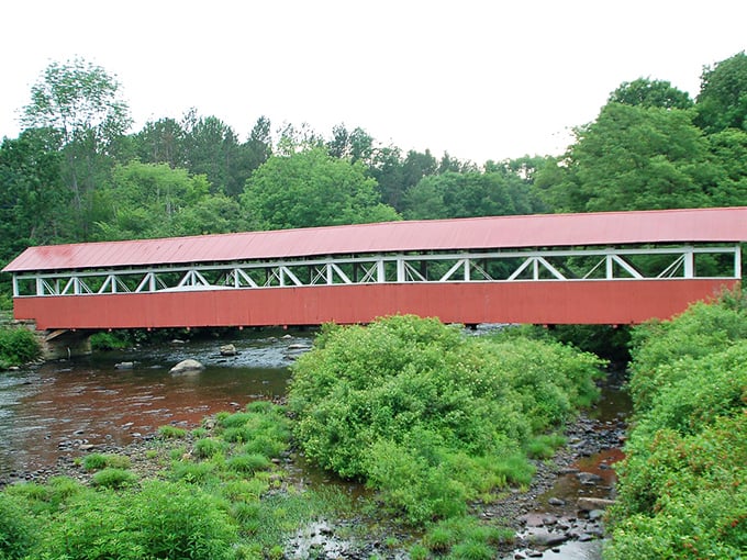 Summer's vibrant greens create a lush frame for the bridge's distinctive profile. The water level changes with seasons, but the beauty remains constant.