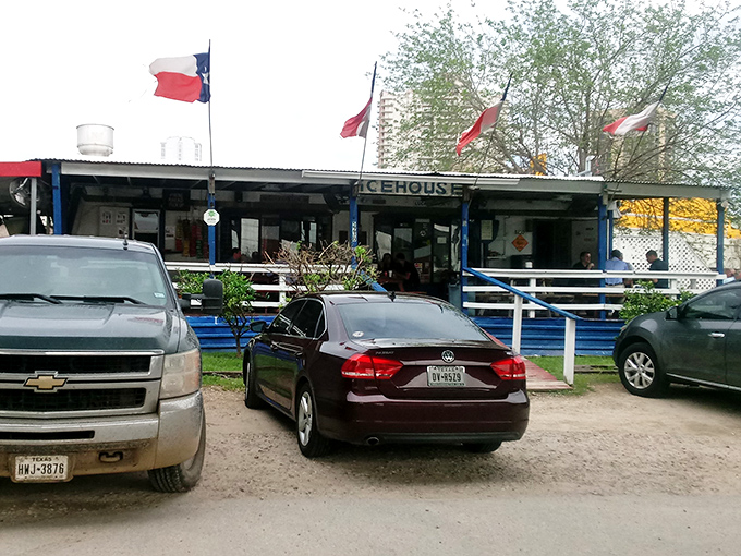 The humble blue shack with Texas flags flying proudly – where burger magic happens beneath Houston's highways.