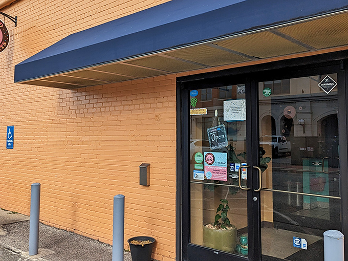 The sunny yellow brick exterior of Glazed Doughnuts beckons like a sweet morning promise. Blue awning, bike-friendly, and bound to brighten your day!