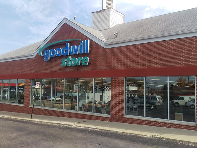 The iconic blue Goodwill sign beckons like a lighthouse for bargain hunters navigating the sea of retail.