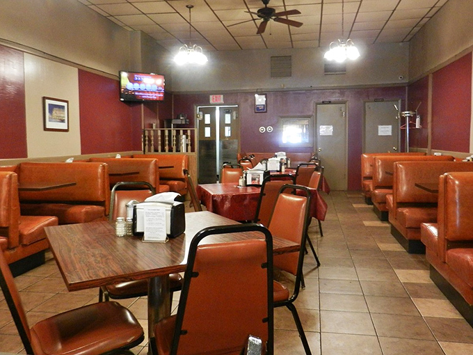 Classic orange vinyl booths create the perfect backdrop for comfort food conversations. This isn't décor – it's a time machine.
