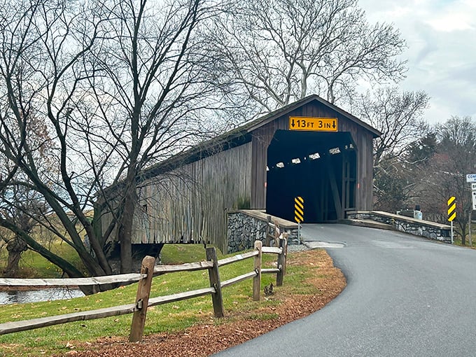 The approach to history—weathered wood, stone foundations, and that iconic yellow clearance sign warning modern vehicles what horse-drawn wagons never worried about.