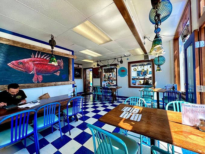 Checkered floors and vibrant blue chairs create the perfect backdrop for seafood adventures. That rockfish painting isn't just watching you eat—it's judging your seafood-to-tartar-sauce ratio.