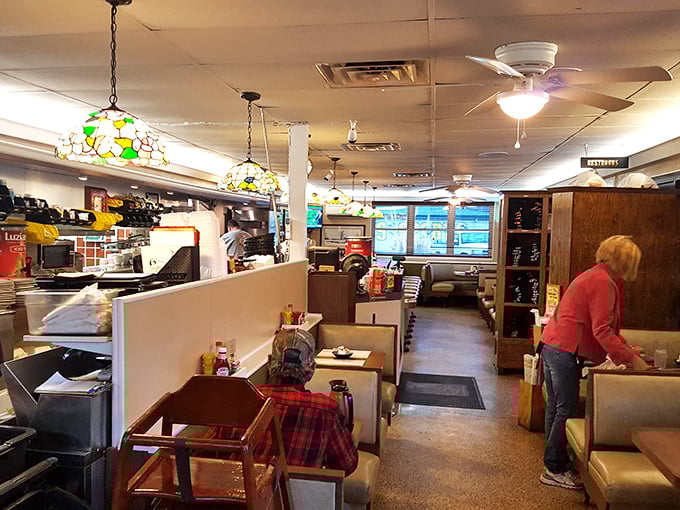 Stained glass pendant lights cast a warm glow over vinyl booths where culinary magic happens. It's like dining in your favorite aunt's kitchen—if she made legendary cheesesteaks.