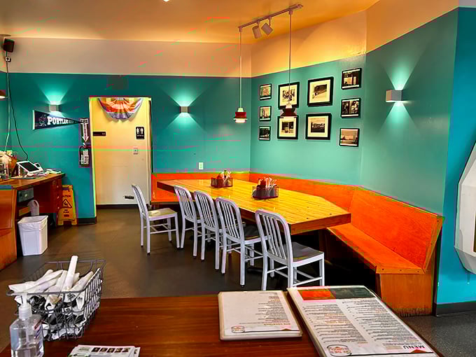 Teal walls embrace wooden tables in a dining space that feels like your coolest friend's kitchen—if that friend had impeccable taste and excellent lighting.