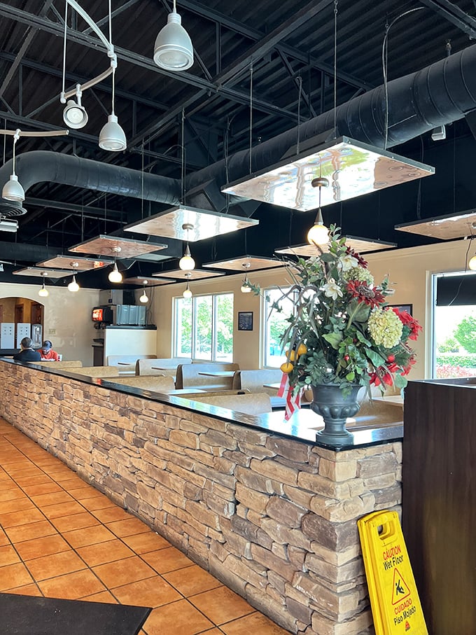 Industrial-chic meets cozy comfort with exposed ductwork above and warm stone below—a perfect backdrop for the pizza magic that happens here.