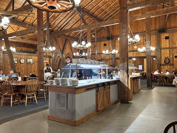 Rustic wooden beams and wagon wheel chandeliers create an authentic barn atmosphere that's both grand and cozy—like dining in a Norman Rockwell painting come to life.