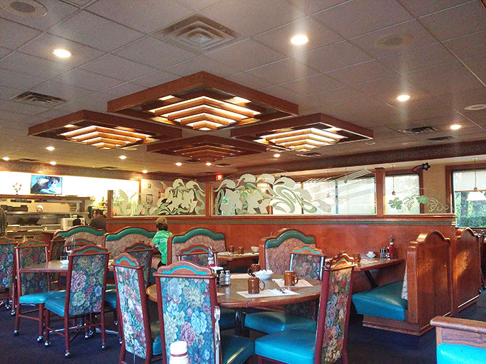 Classic diner aesthetics meet cozy comfort with those distinctive tiered ceiling lights. The floral upholstery isn't trying to be retro—it just never left, thank goodness.