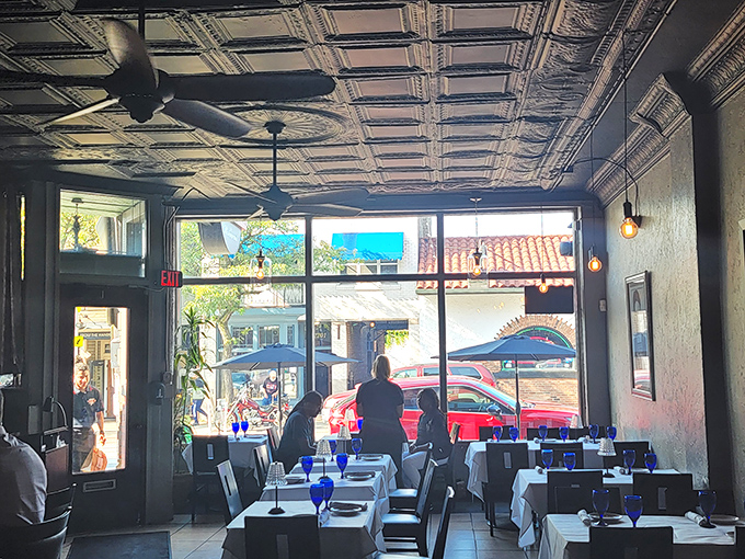Sunlight streams through large windows, illuminating the elegant interior where pressed tin ceilings and cobalt blue glassware create an atmosphere that's both sophisticated and welcoming.