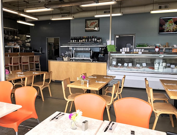 Orange chairs pop against wooden tables in this bright, airy space. The fish market counter reminds you that "fresh" isn't just marketing—it's their mission.