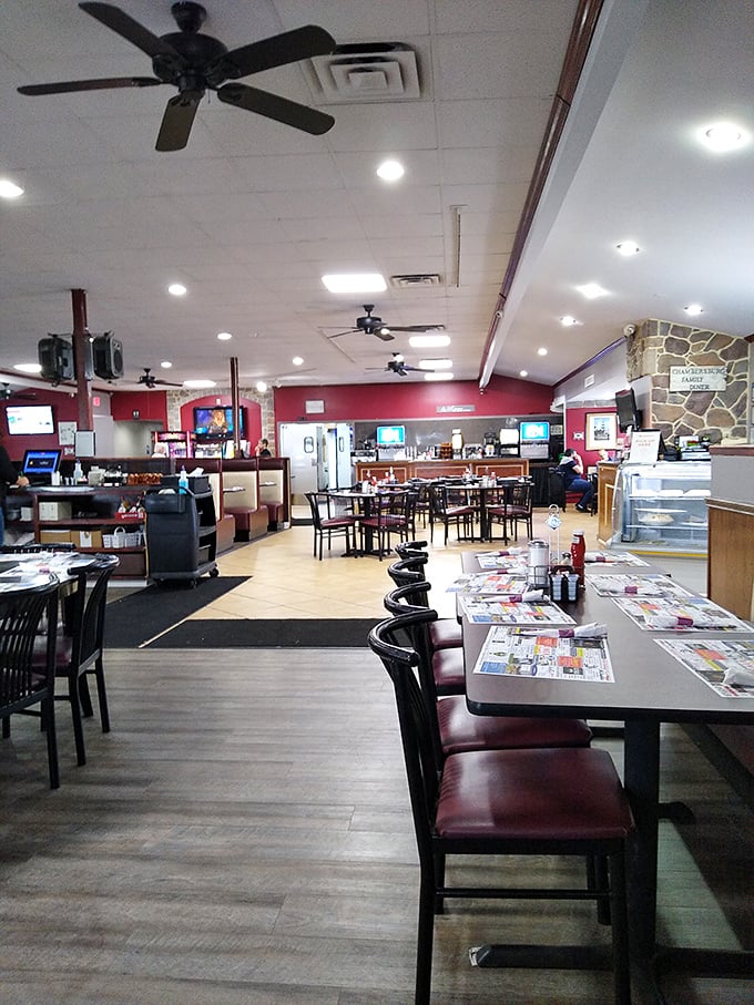 Classic diner ambiance with ceiling fans, burgundy booths, and paper placemats—the universal signal that affordable deliciousness is imminent.