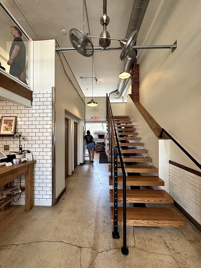 A modern industrial staircase leads upward, while white subway tiles and warm wood create that perfect balance of rustic charm and contemporary cool.