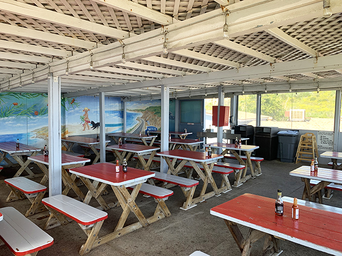 Red-topped picnic tables await beneath a latticed ceiling adorned with coastal murals. Fancy? No. Perfect? Absolutely.