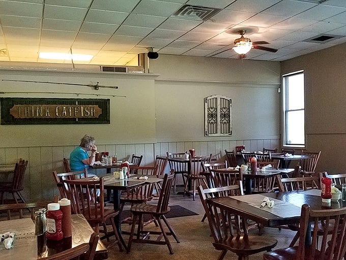 "THINK CATFISH" isn't just wall decor—it's a life philosophy at this no-frills dining room where wooden chairs and ceiling fans set the perfect unpretentious stage.